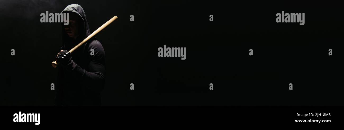 Silhouette of african american bandit in hoodie holding baseball bat ...