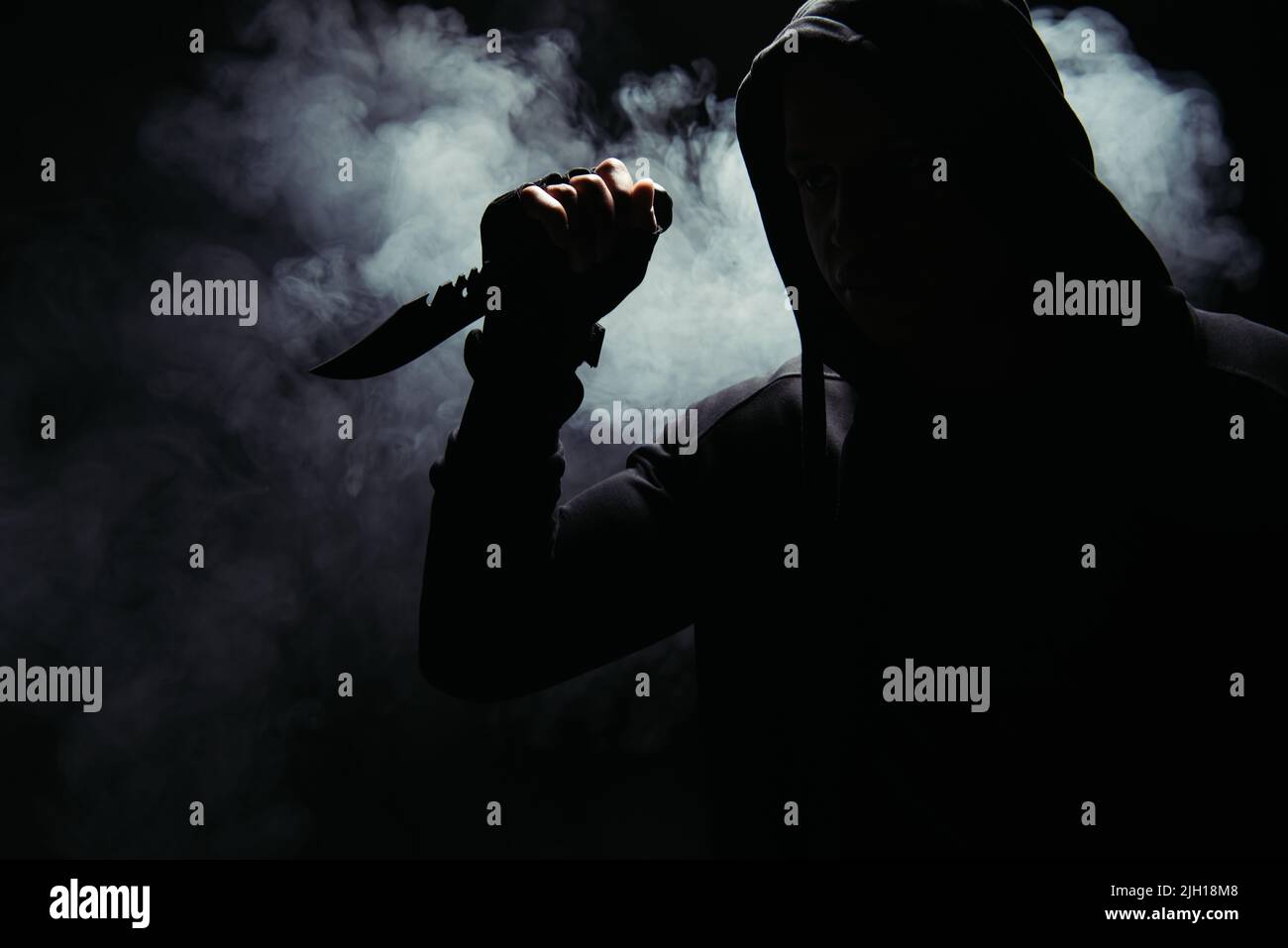 Silhouette of african american bandit in hood holding knife on black ...