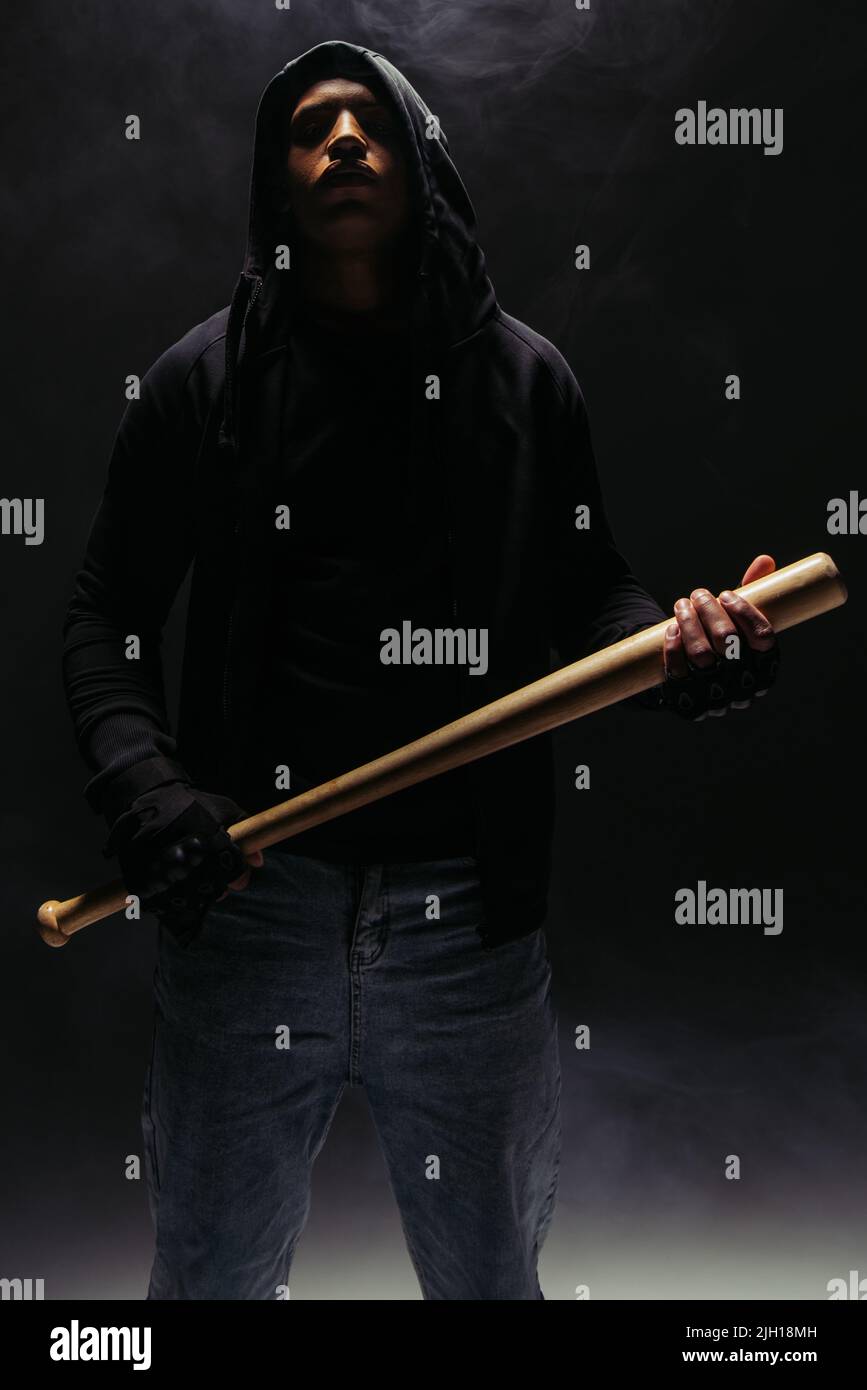 African american bandit in hood holding baseball bat on black ...
