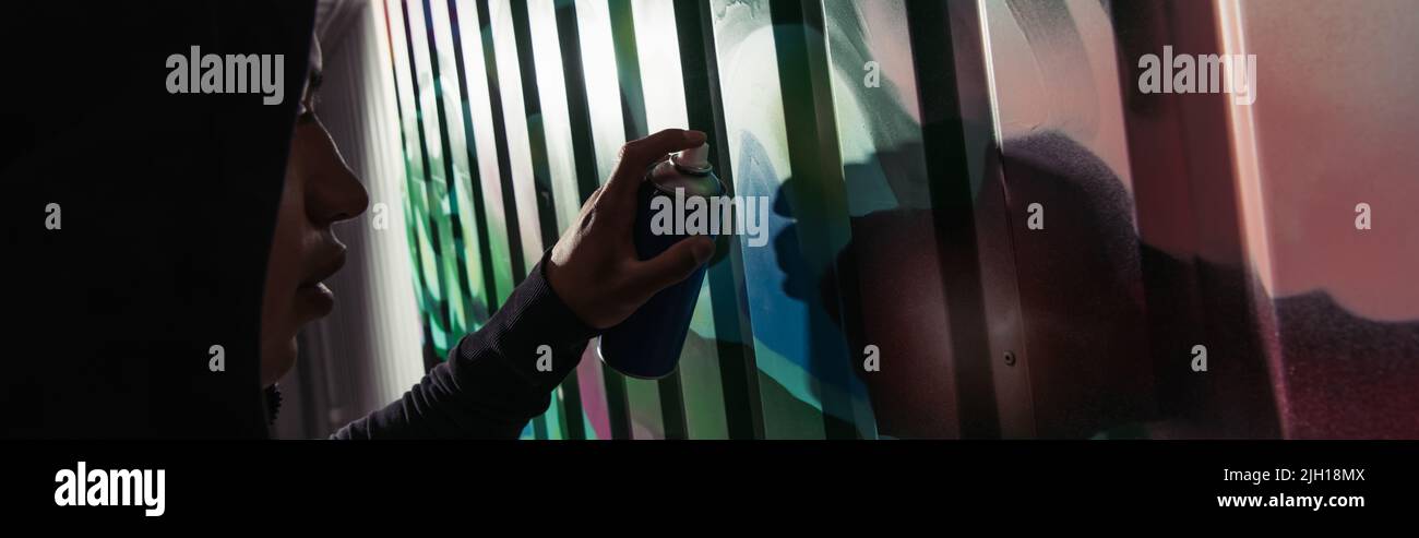 Side view of african american vandal drawing graffiti on wall, banner ...