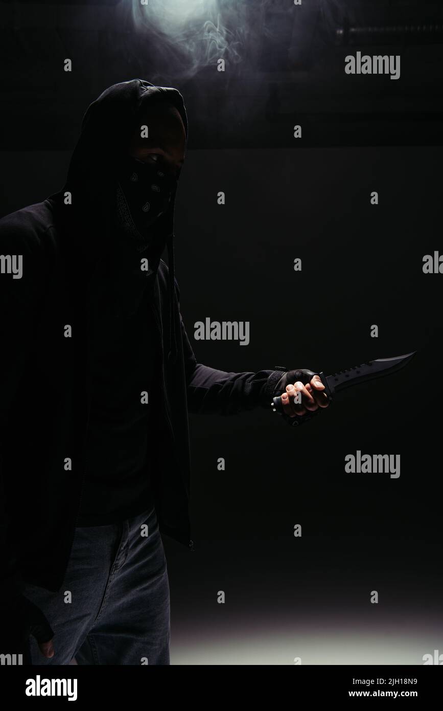 Silhouette of african american robber in mask and hoodie holding knife ...