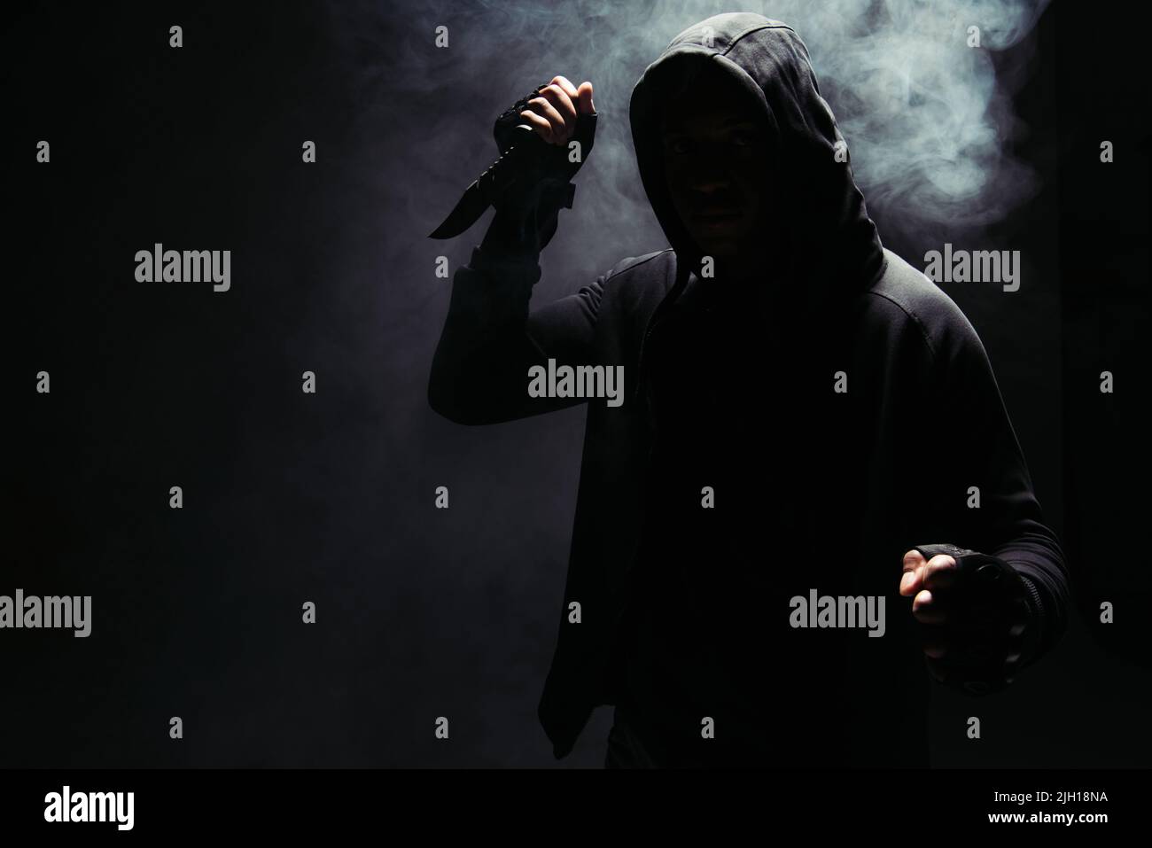 Silhouette of african american bandit in hoodie holding knife on black ...