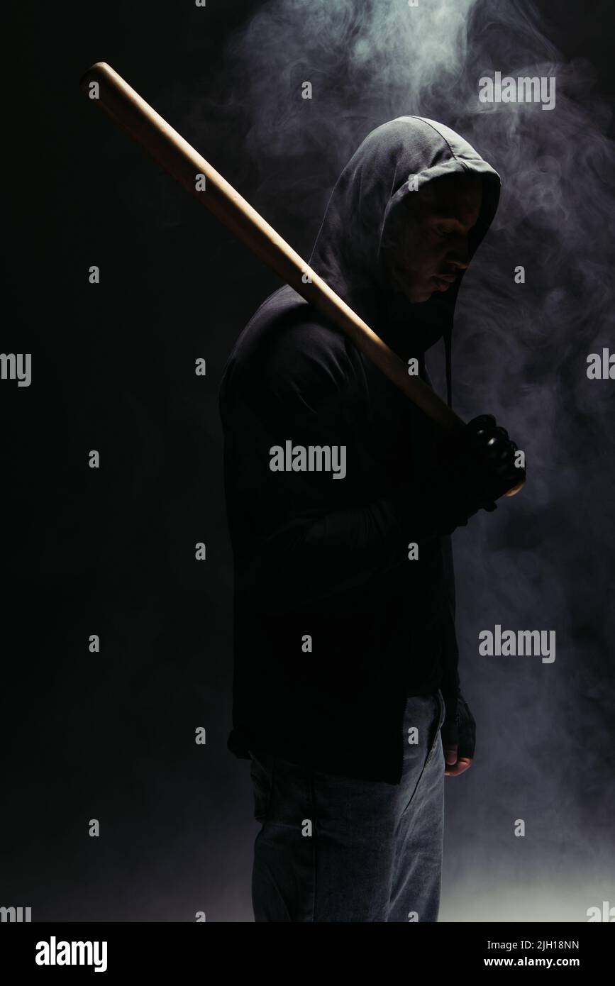 Side view of silhouette of african american bandit holding baseball bat ...