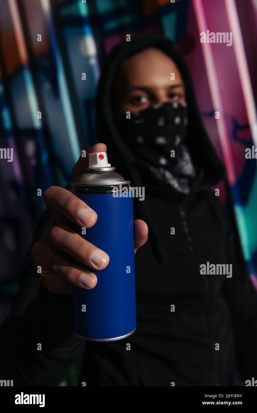 Blurred african american vandal with mask on face holding spray paint ...