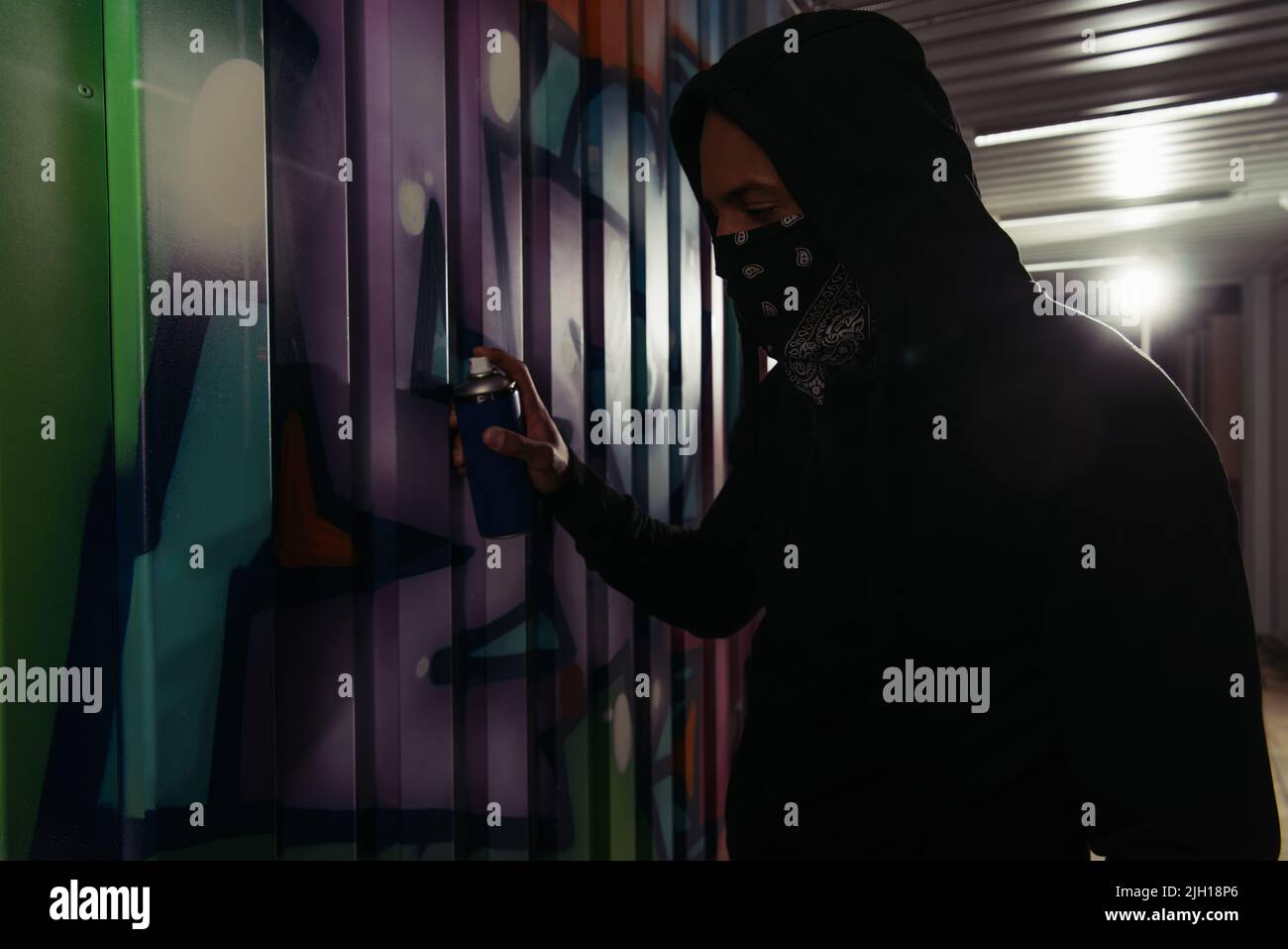 Side view of african american hooligan in hoodie and mask drawing ...