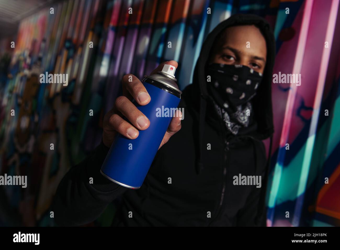 Blurred african american vandal holding spray paint near graffiti on ...