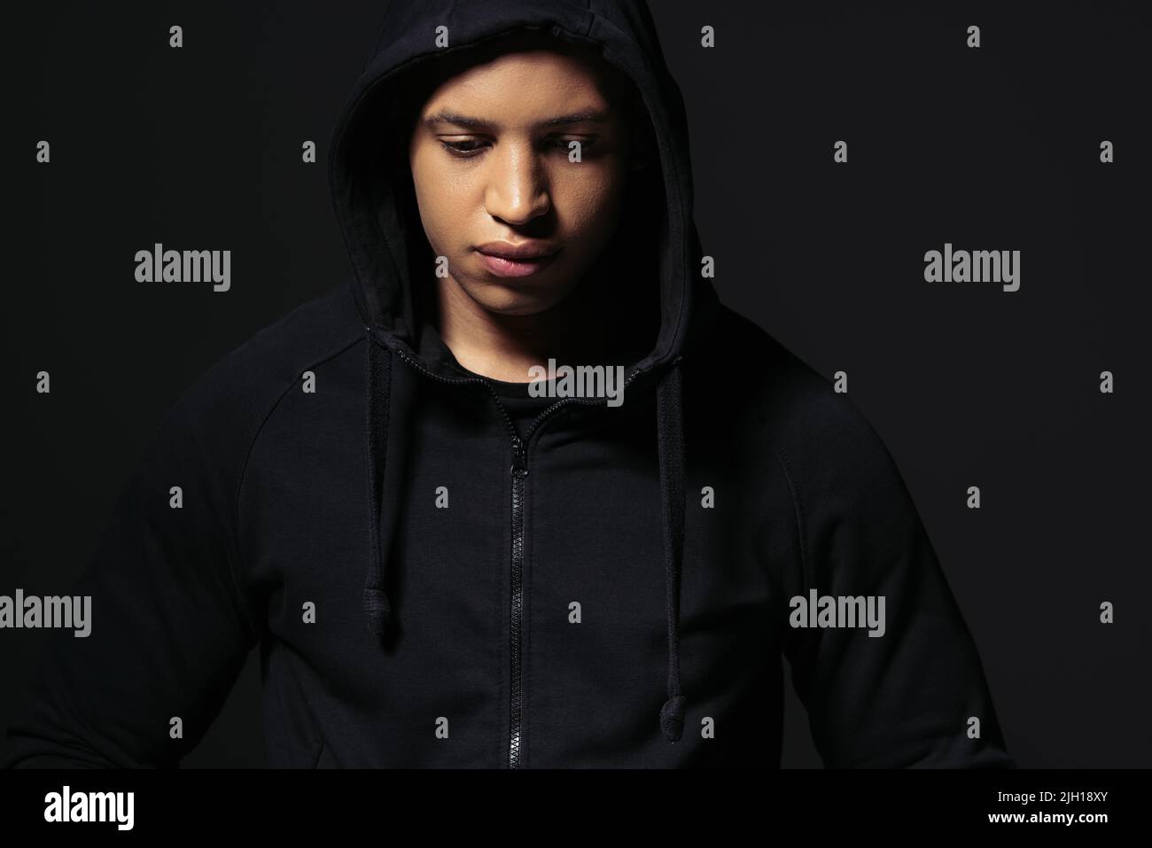 African american hooligan in hoodie standing isolated on black Stock ...