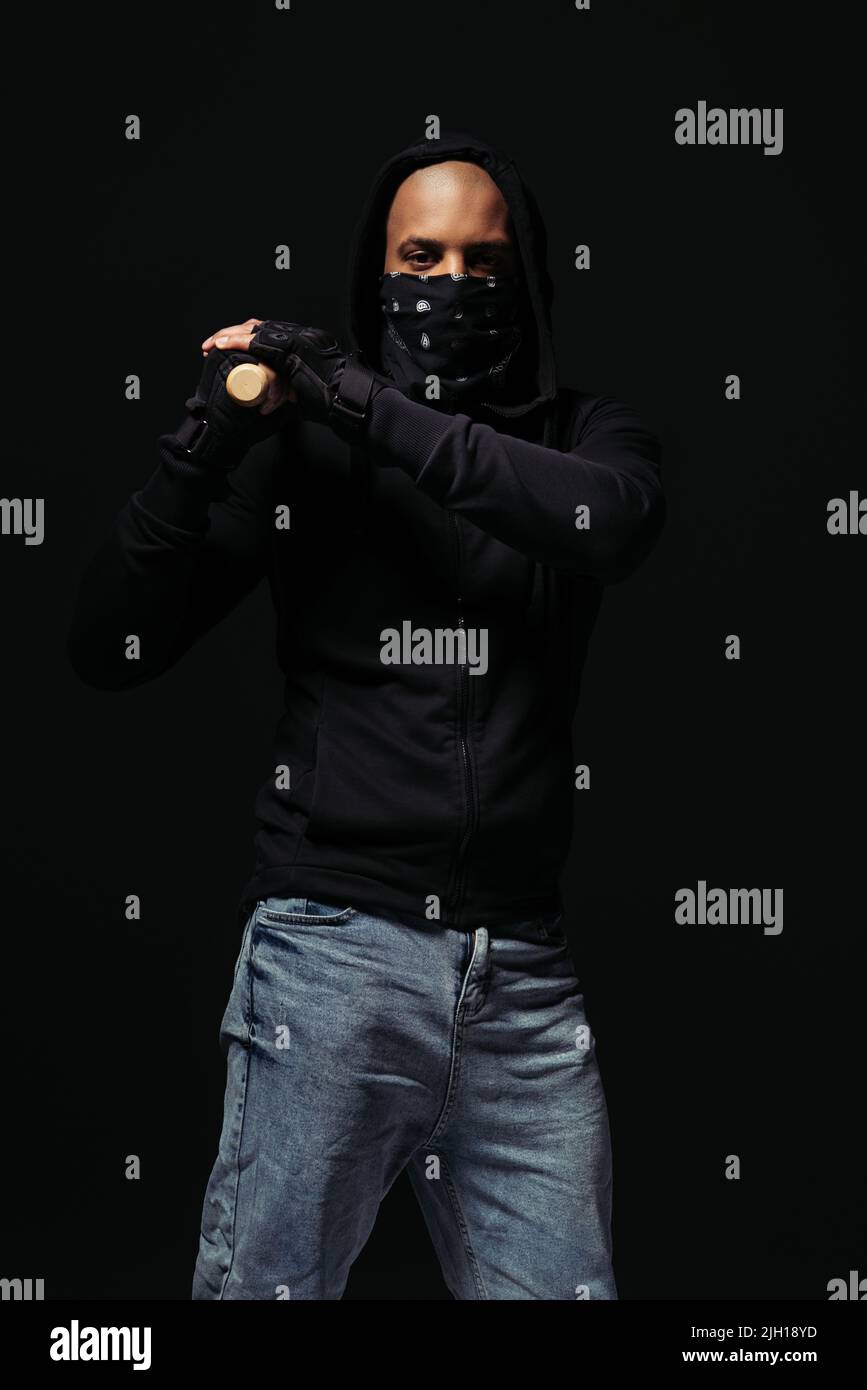 African american hooligan in gloves and face mask holding baseball bat ...