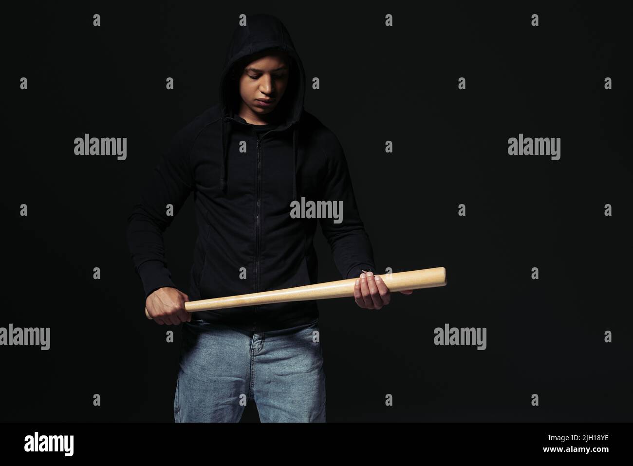 African american hooligan in hoodie looking at baseball bat isolated on ...