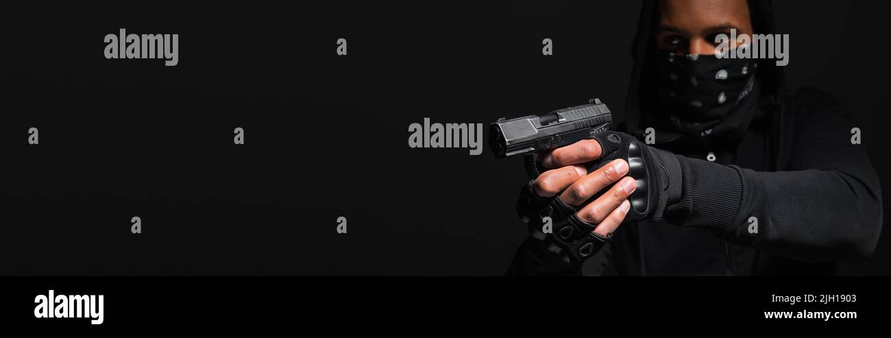 Blurred african american bandit holding handgun isolated on black ...