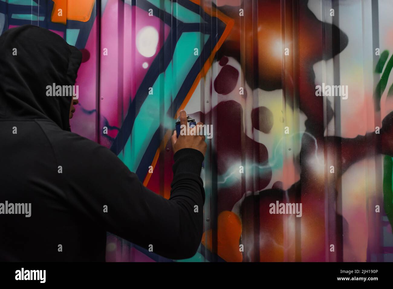 African american hooligan drawing graffiti on wall on street Stock ...