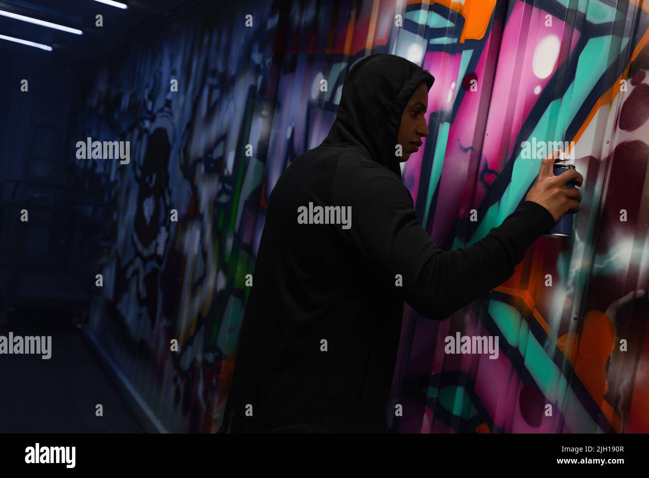 Side view of african american vandal painting graffiti on wall Stock ...