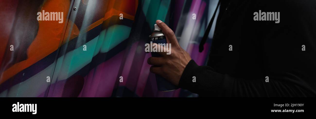 Cropped view of african american vandal painting graffiti on urban ...