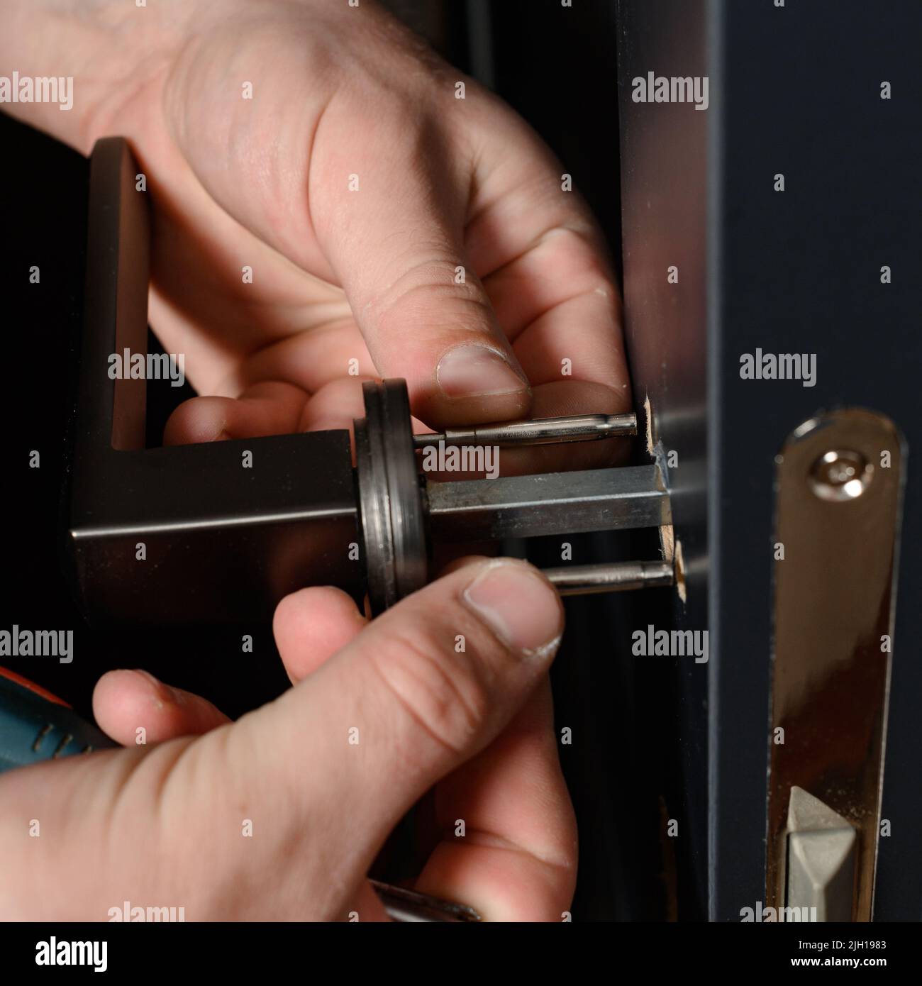 A man installs a door handle in a door, carpentry work at home, repair ...