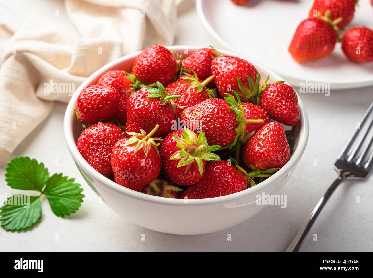 Strawberries in a white bowl on a light background. Side view, close-up ...