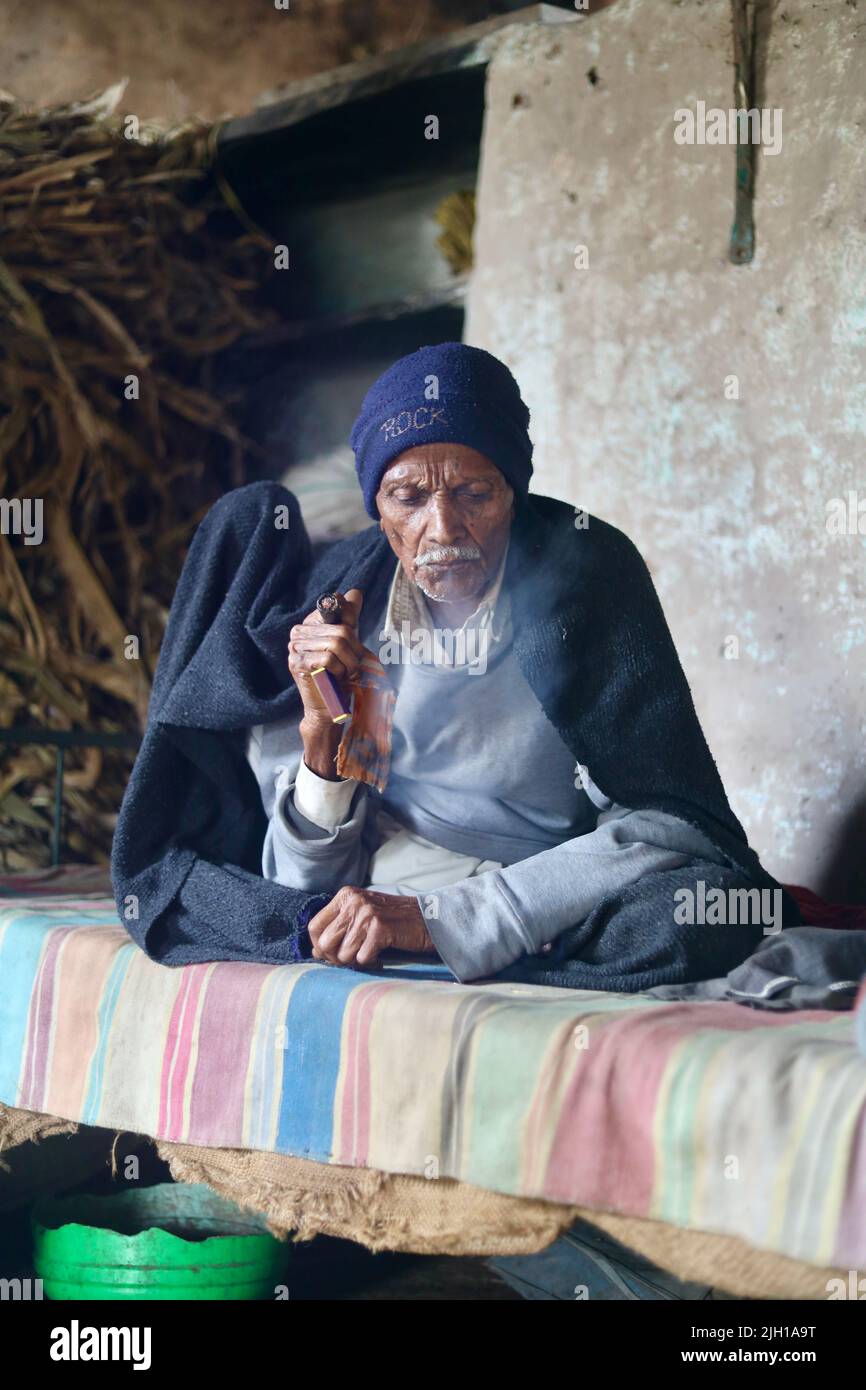 A selective focus of an Indian poor village old man smoking Chillum ...