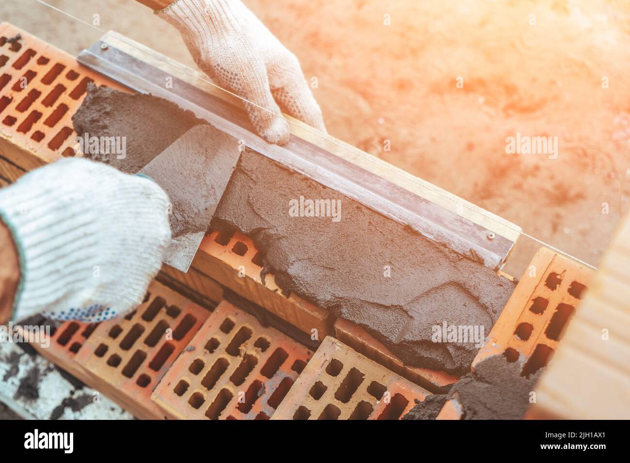 Worker or bricklayer works with trowel laying bricks. Builder makes ...