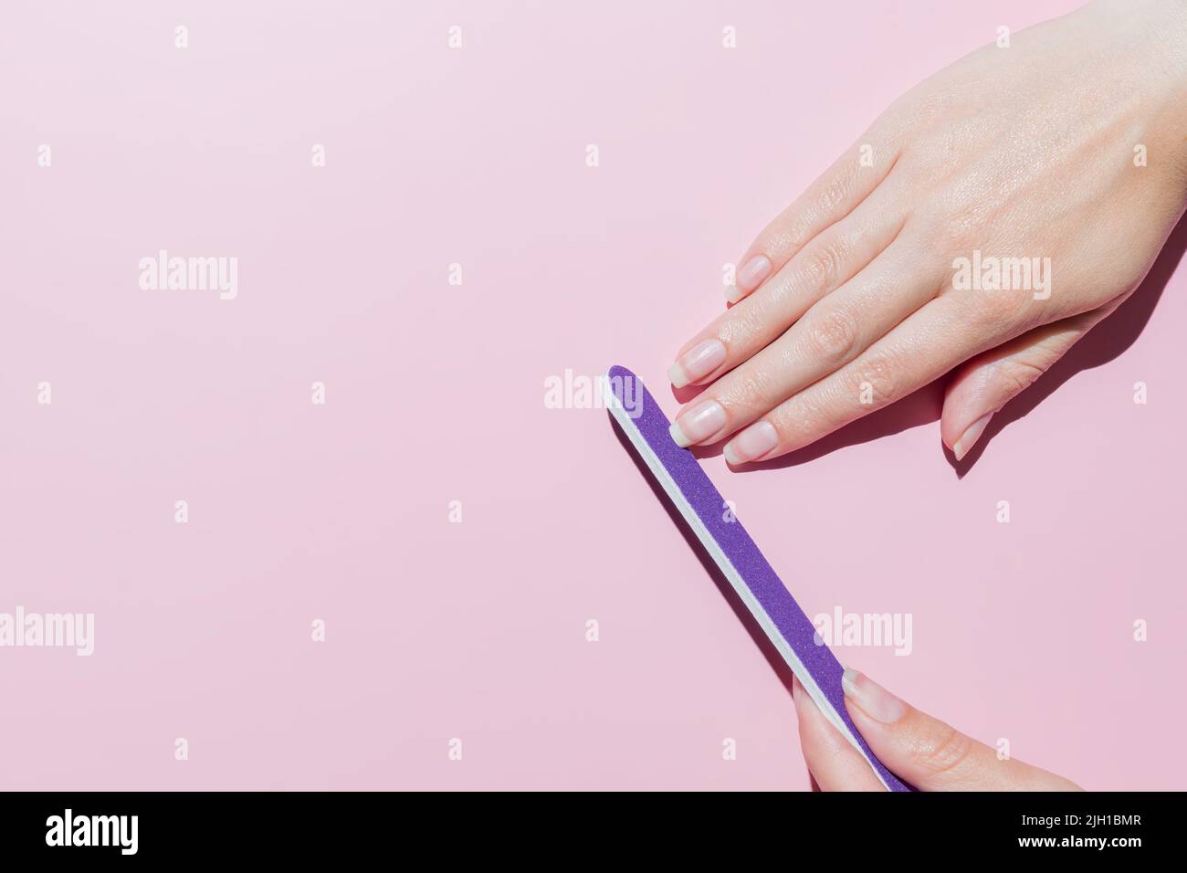 woman filing her nails with purple fimger file, making manicure at home ...