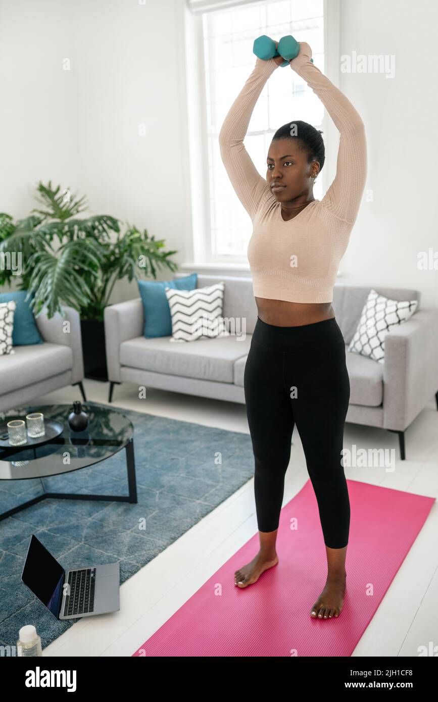 Black African woman exercising at home. Doing weighted dumbbell workout ...