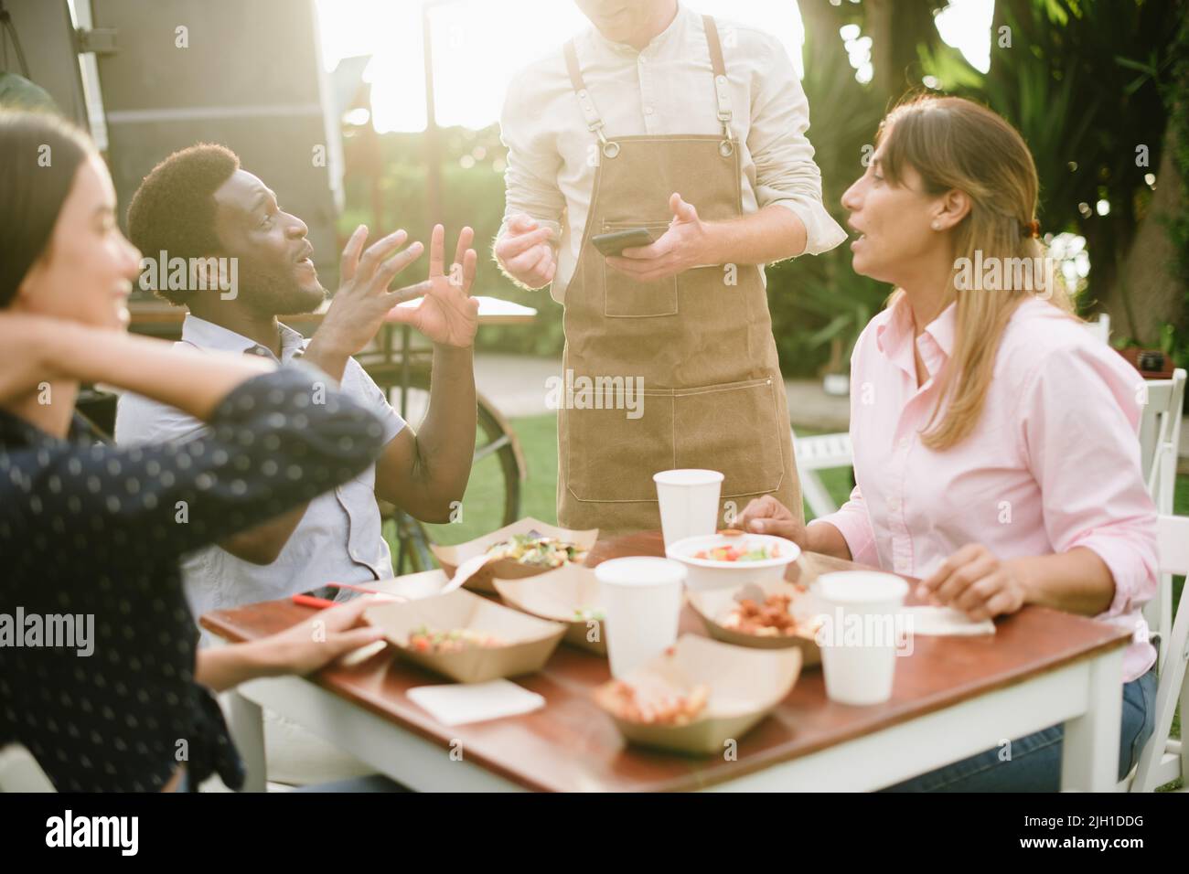 Diverse friends speaking with waiter Stock Photo - Alamy