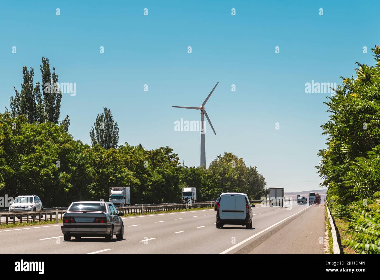 Clean energy wind turbine installed next to the highway Stock Photo - Alamy