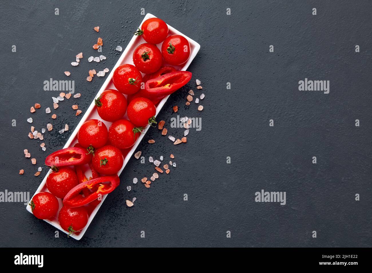 Fresh washed cherry tomatoes and paprika slices on a white oblong dish ...
