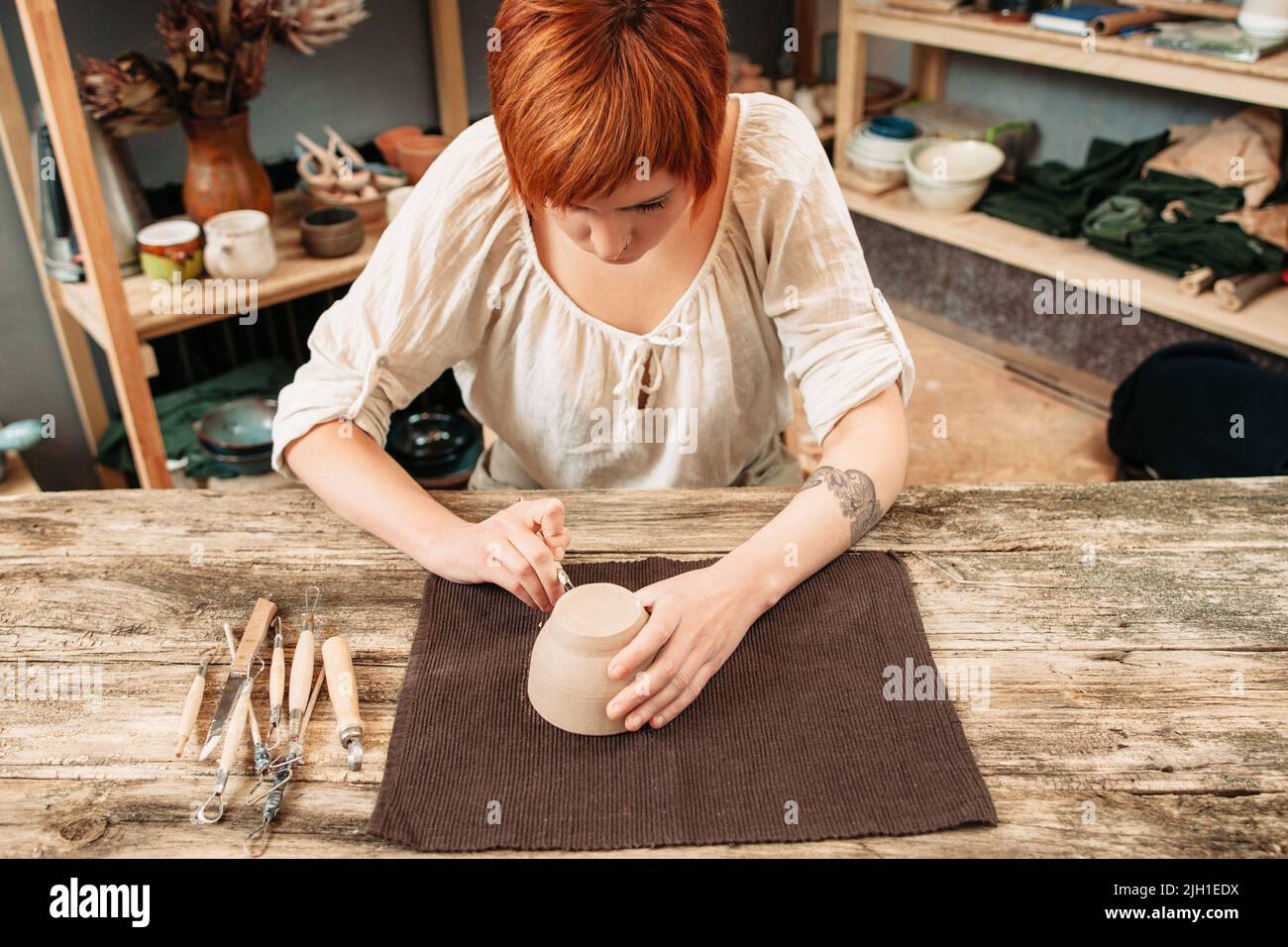 Intently carving on clay pot artisan, pottery making process. Young ...