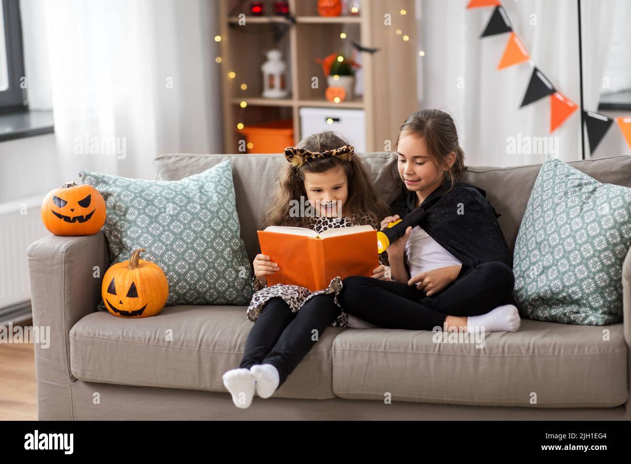 girls in halloween costumes reading book at home Stock Photo - Alamy