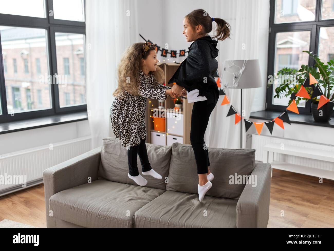 girls in halloween costumes jumping on sofa Stock Photo - Alamy