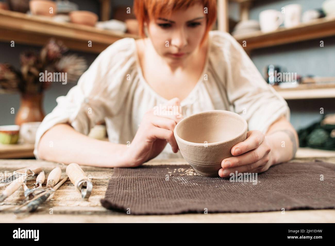 Clay bowl decoration, carving on pottery. Young craftswoman finishing ...
