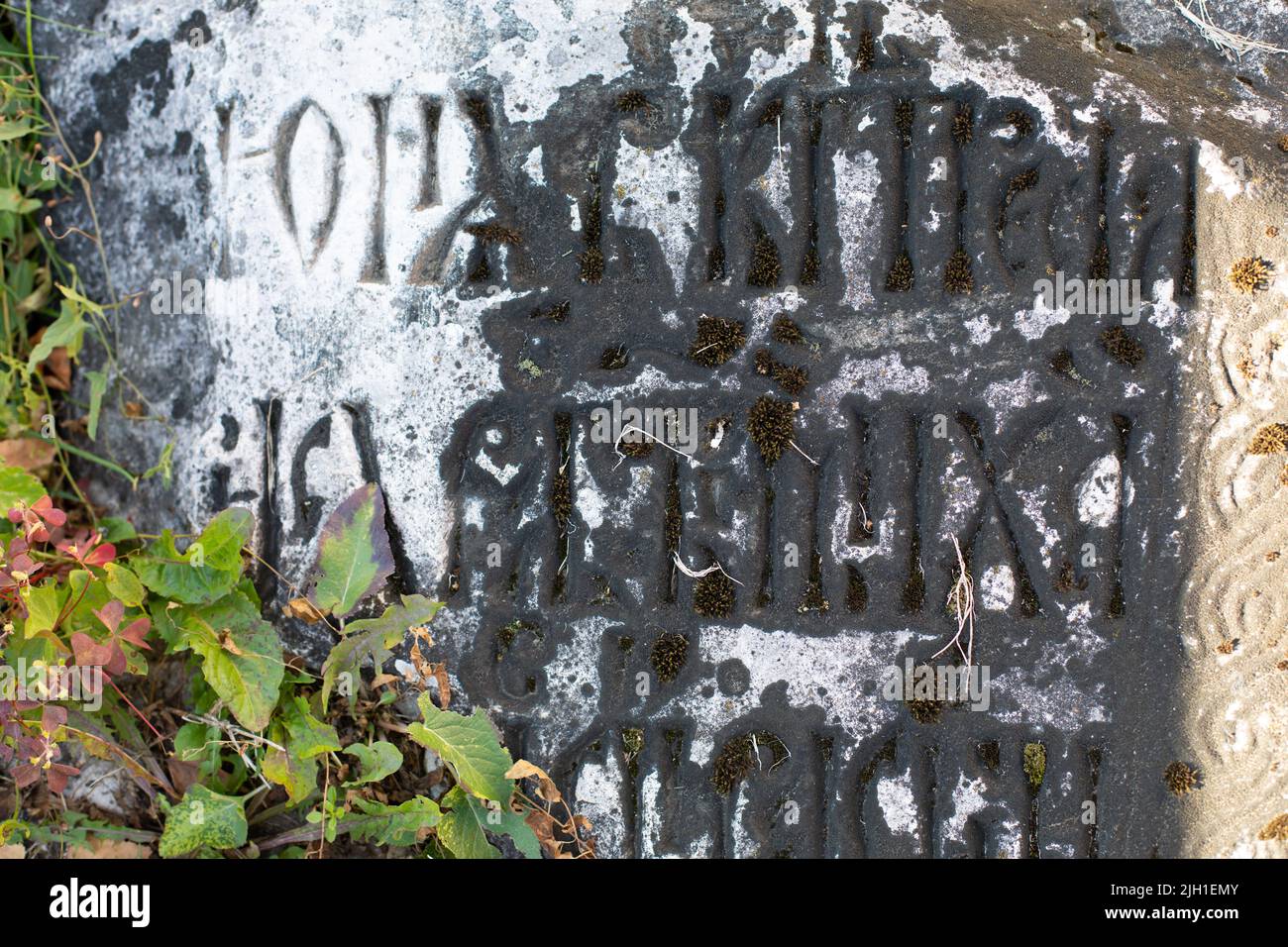 An inscription in Old Slavonic on an old scratched tombstone close-up ...