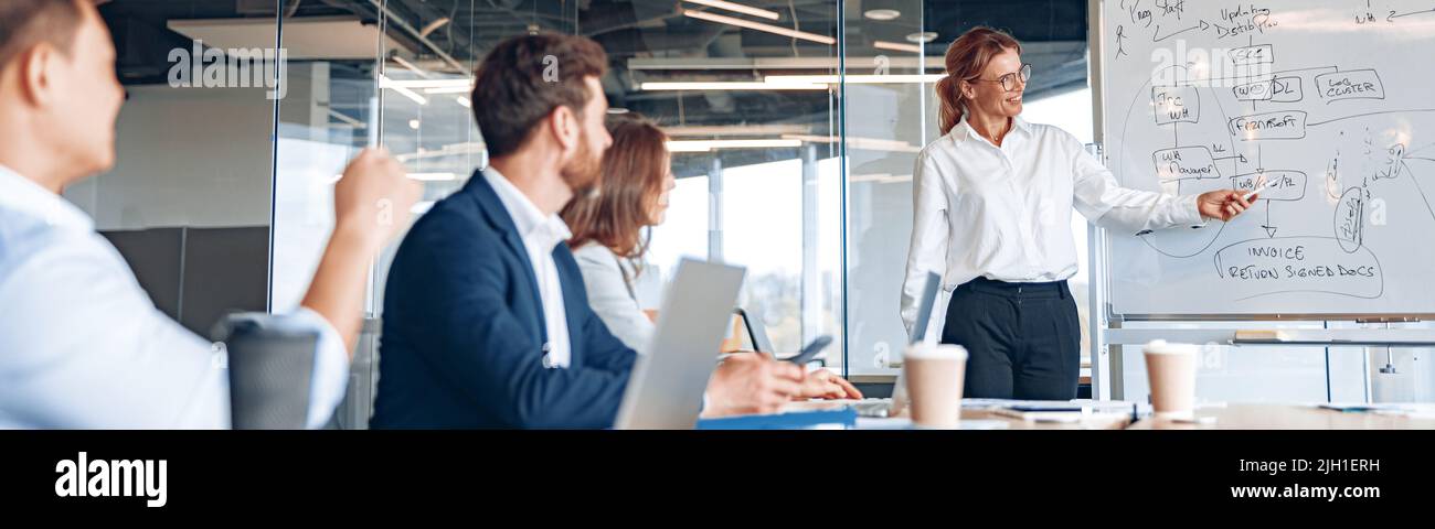 Skilled smiling female leader coaching interested business people ...