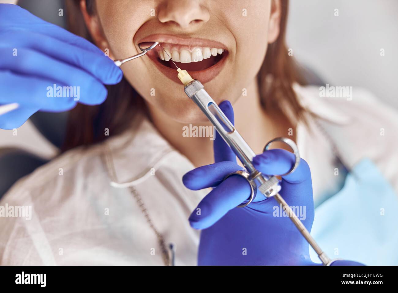 Professional male doctor is doing anestetic injection to happy female ...