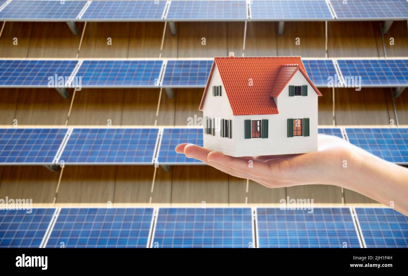hand holding house model over solar panels Stock Photo - Alamy