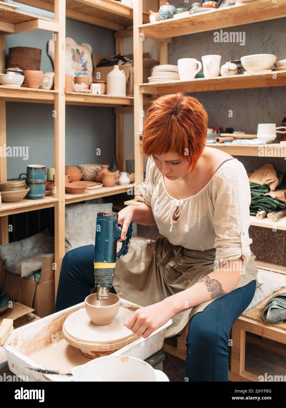 Female potter drying clay bowl with special device at her workshop ...