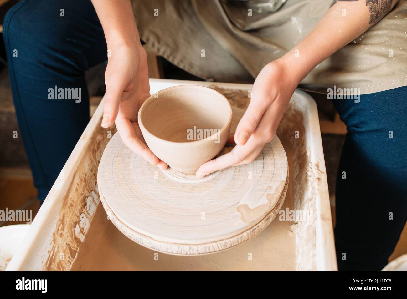 Craftsman taking clay bowl off pottery wheel. Complete handmade ...