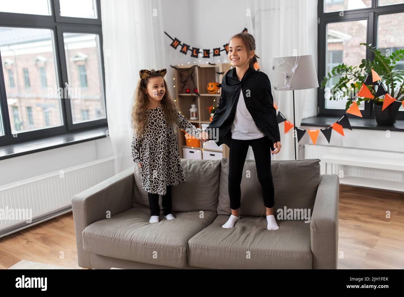 girls in halloween costumes jumping on sofa Stock Photo - Alamy