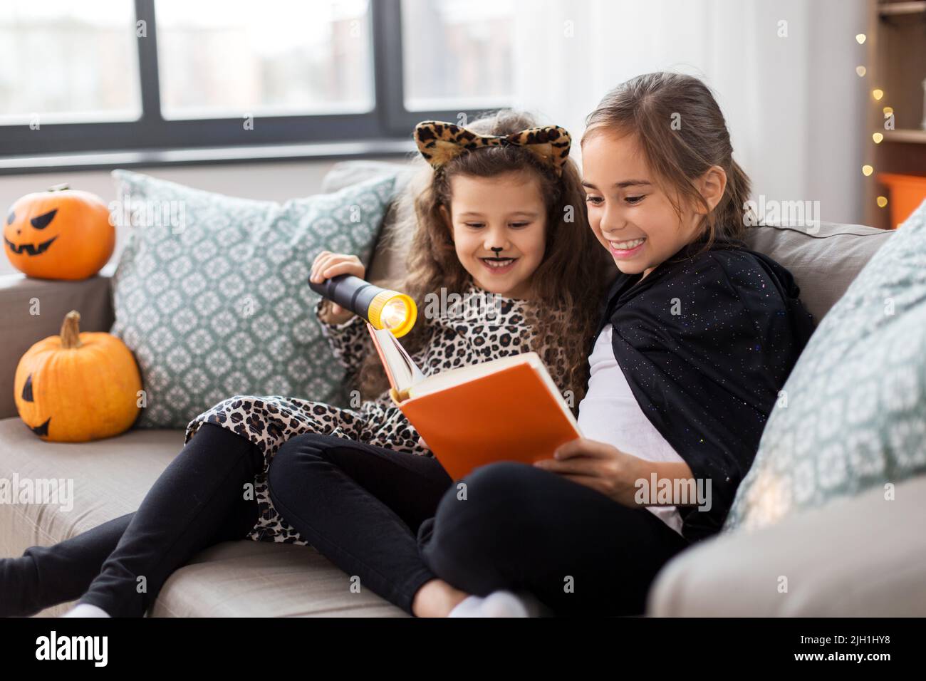 girls in halloween costumes reading book at home Stock Photo - Alamy