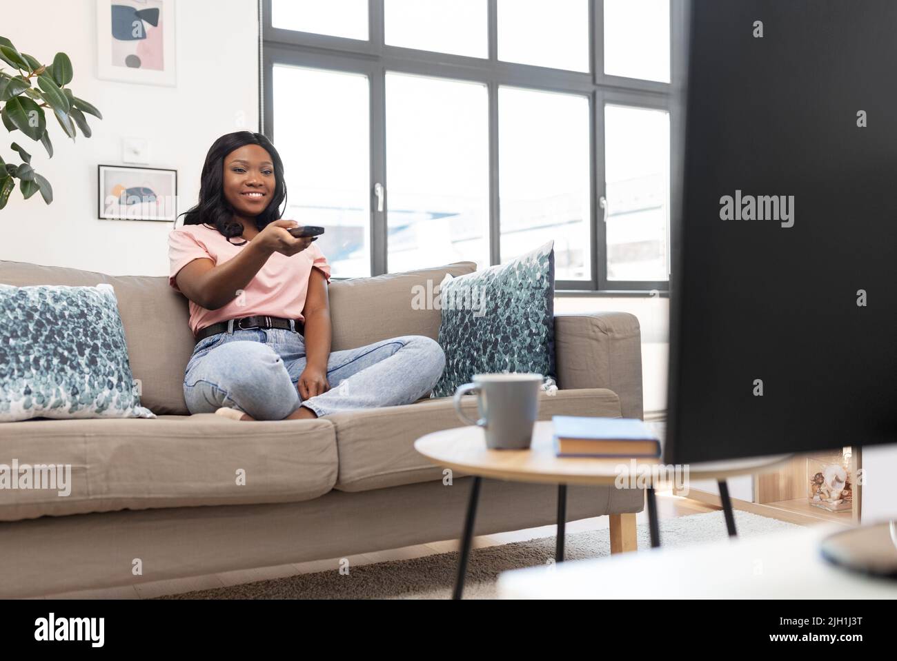 happy african american woman watching tv at home Stock Photo - Alamy