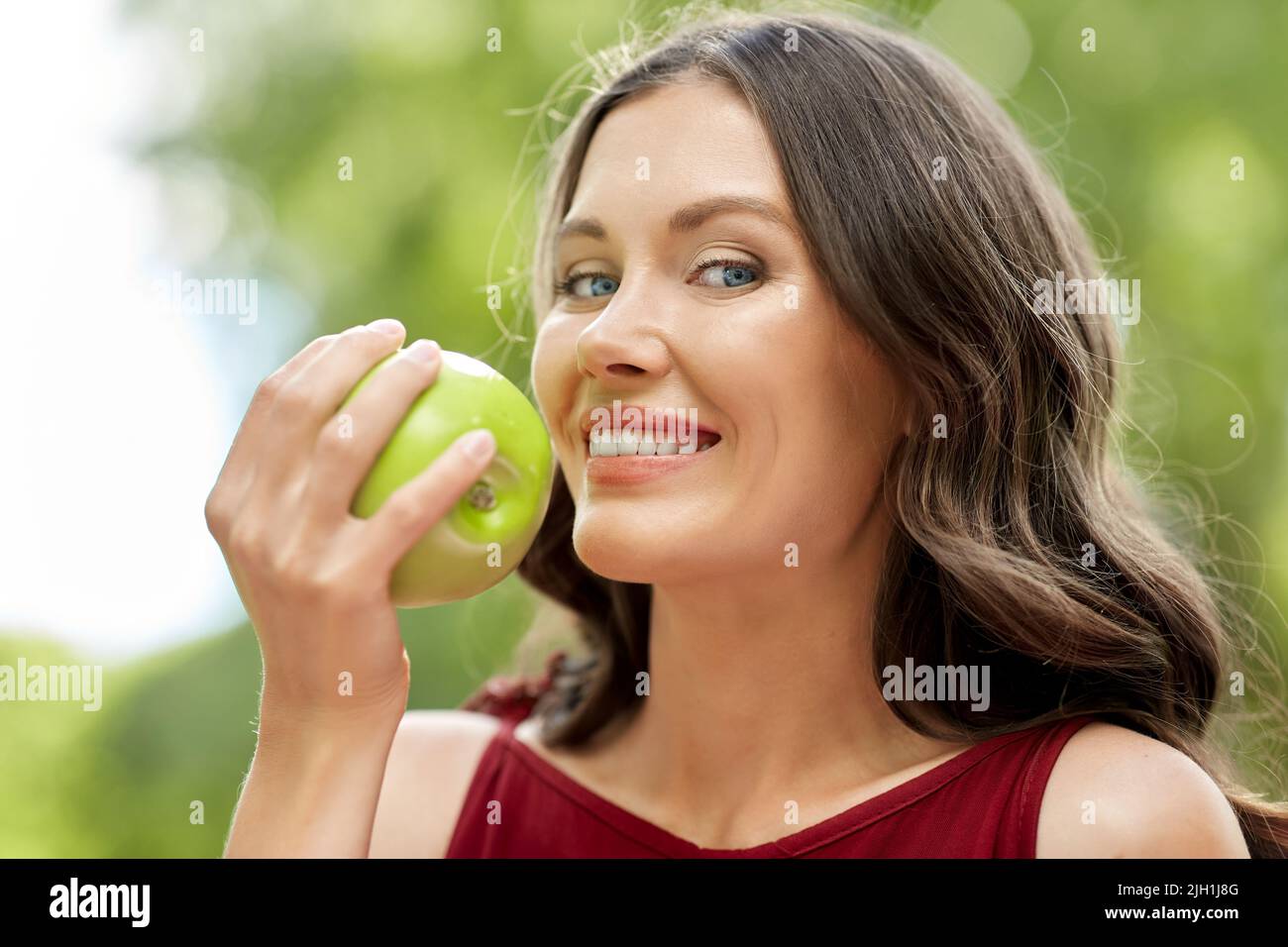 happy woman eating green apple at summer park Stock Photo - Alamy