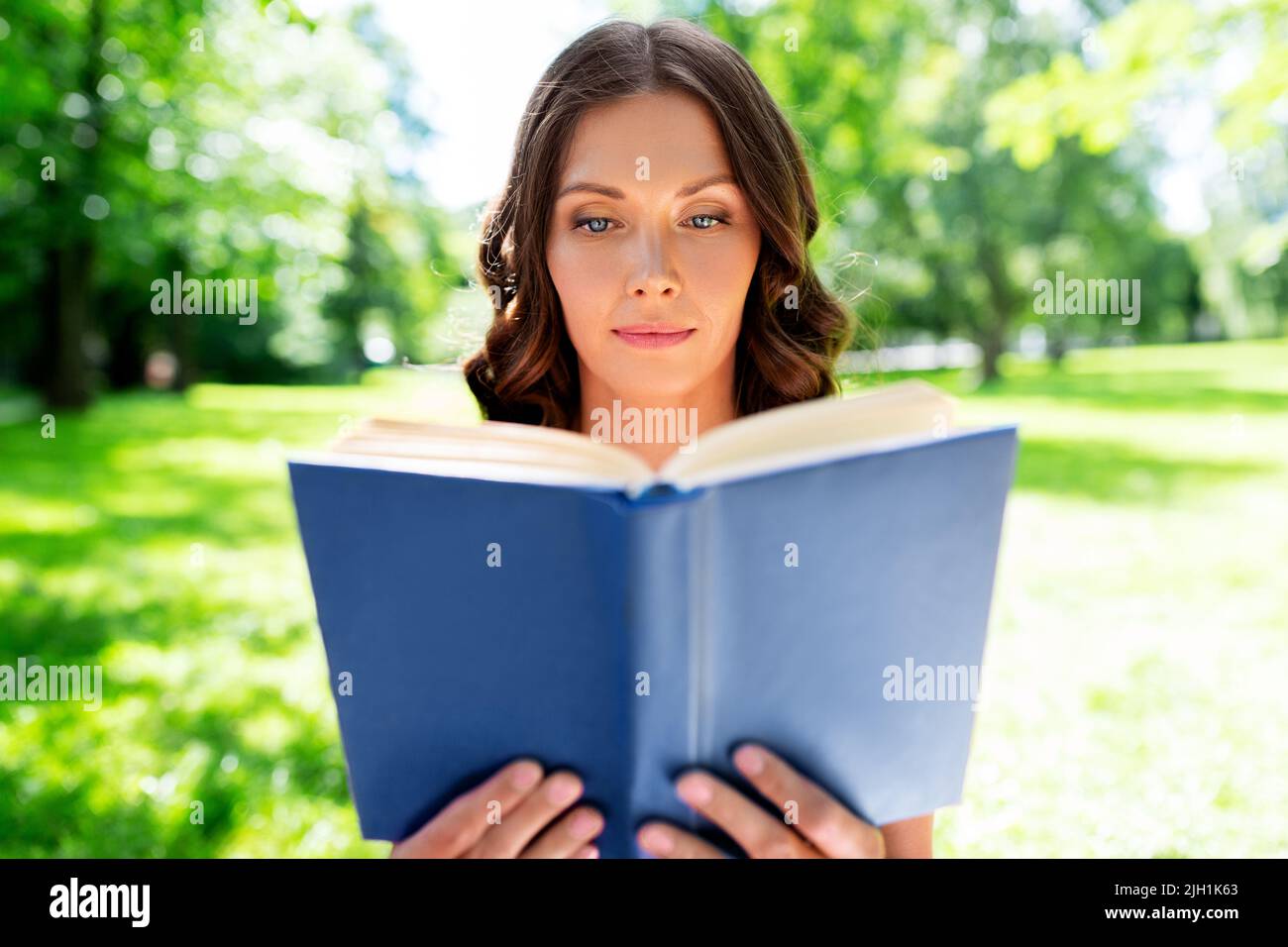beautiful young woman reading book at summer park Stock Photo - Alamy