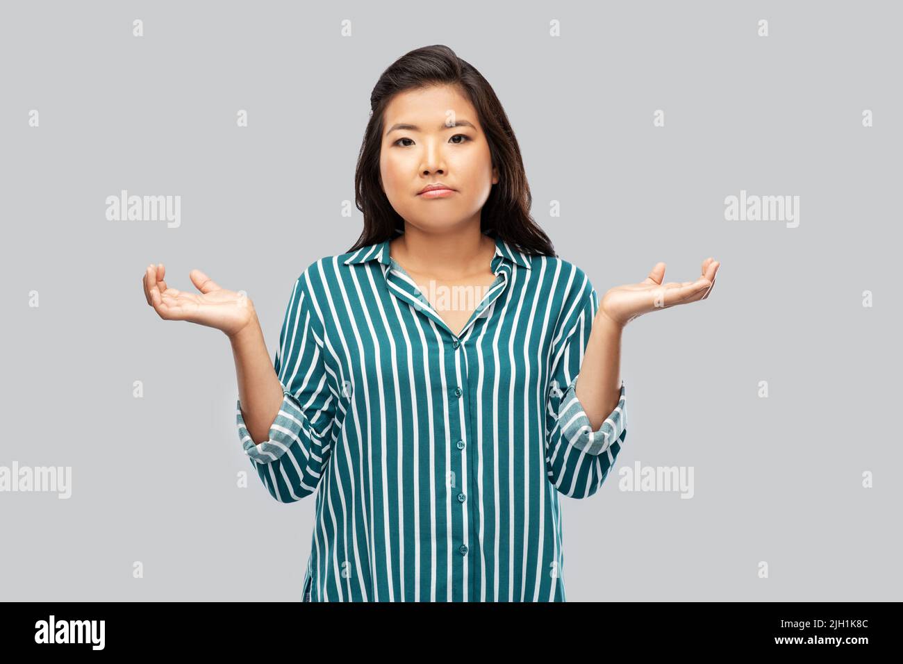 sad asian woman shrugging over grey background Stock Photo - Alamy