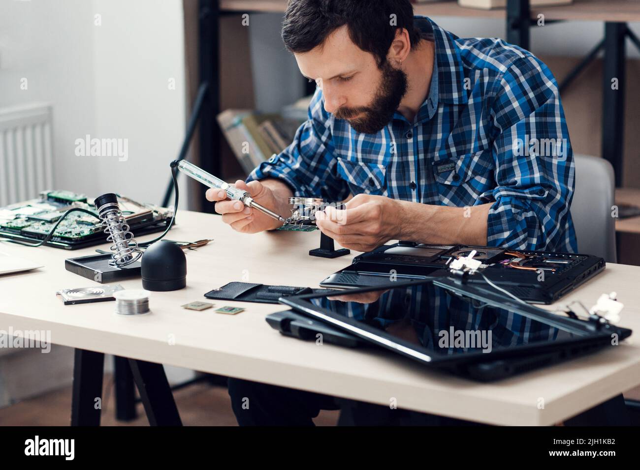Engineer soldering microcircuit though magnifier Stock Photo - Alamy