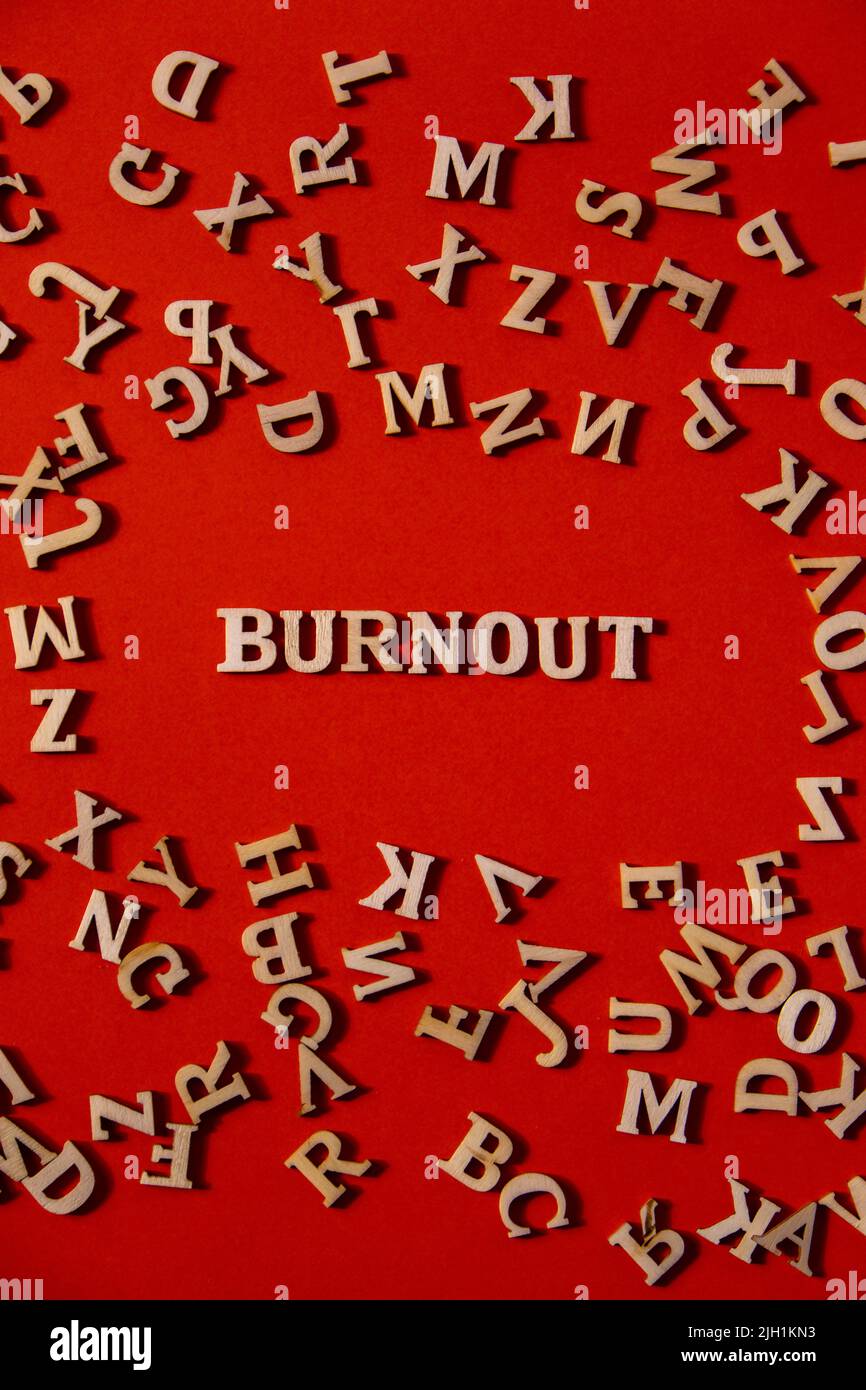 Word BURNOUT made out of wooden letters on bright red background ...