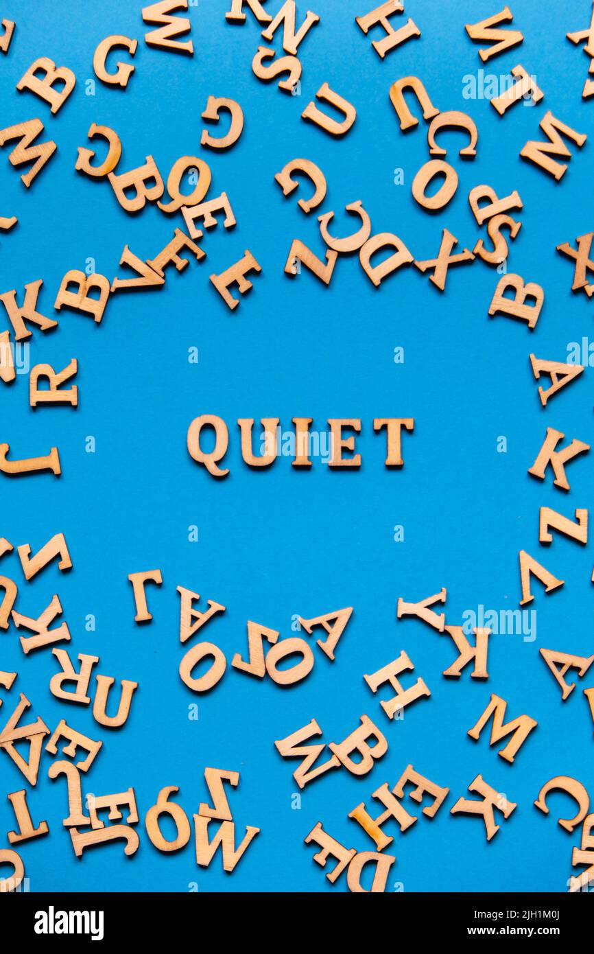 Word QUIET made out of wooden letters on bright blue background ...