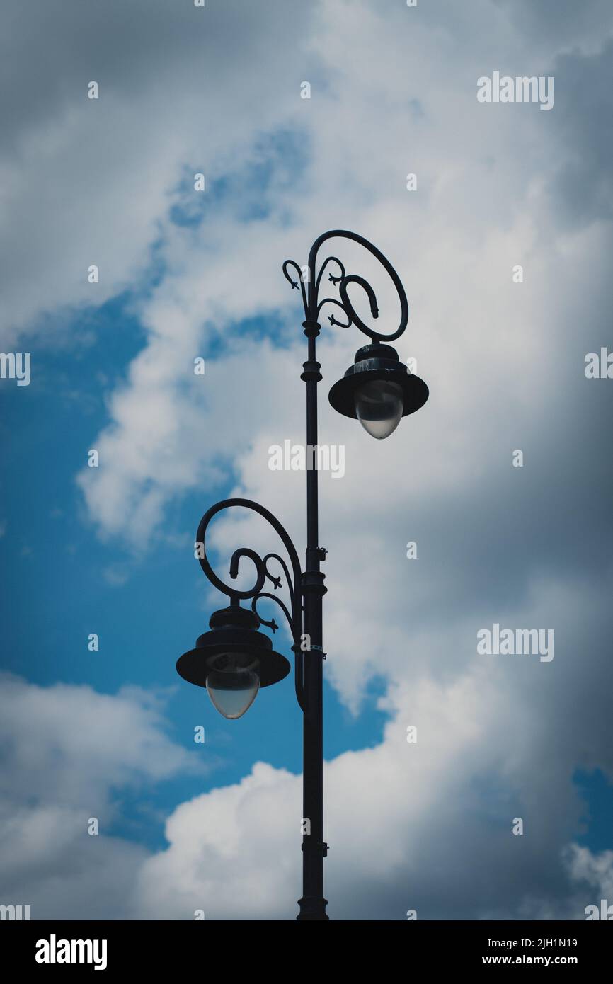 A vertical shot of lamp post against blue cloudy sky background Stock ...