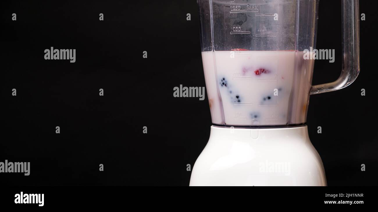 Milkshake in a bowl of a blender of milk, strawberries and blackberries ...