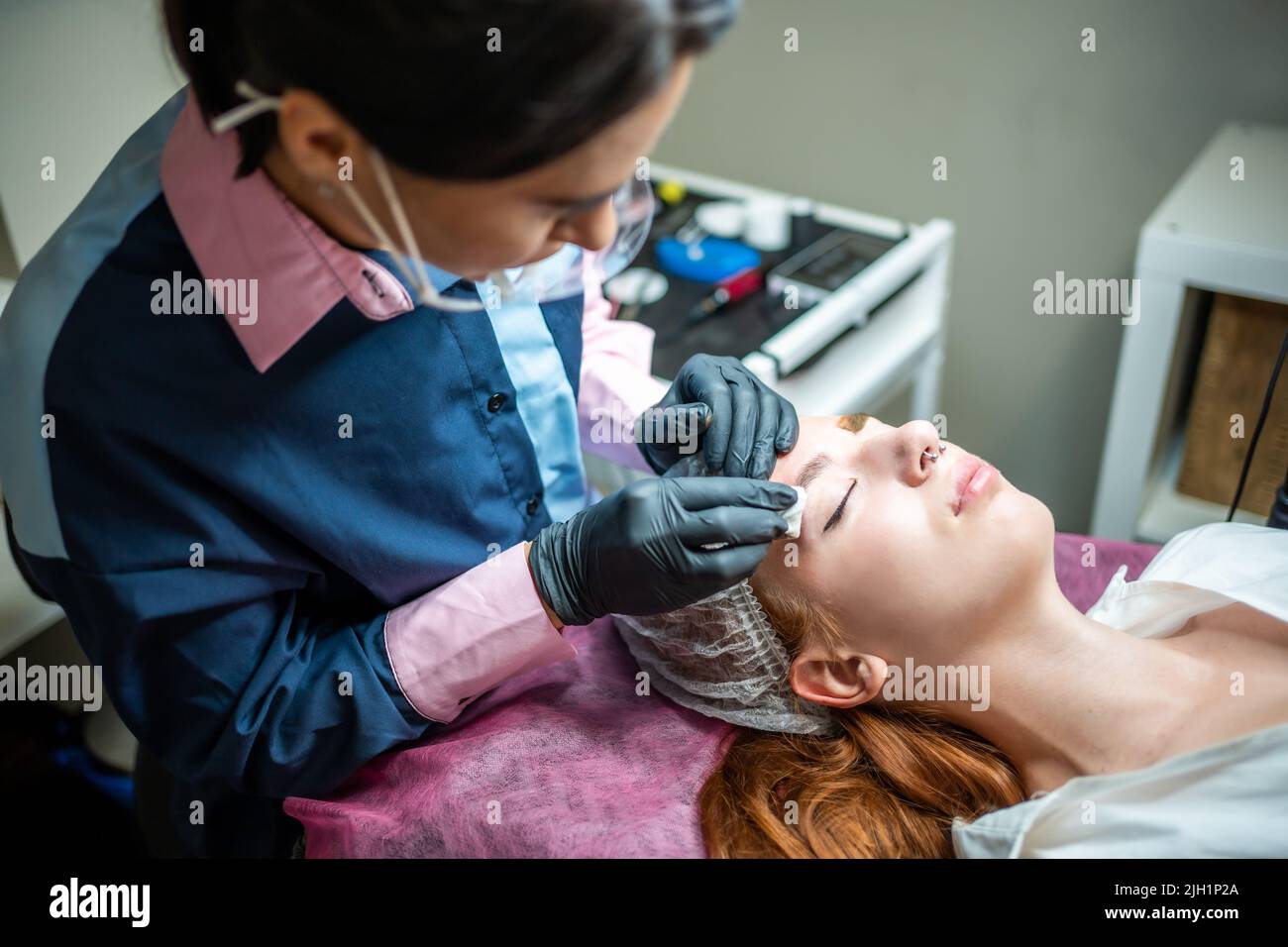 Procedure of eyebrow microblading. A master in black gloves is doing a ...