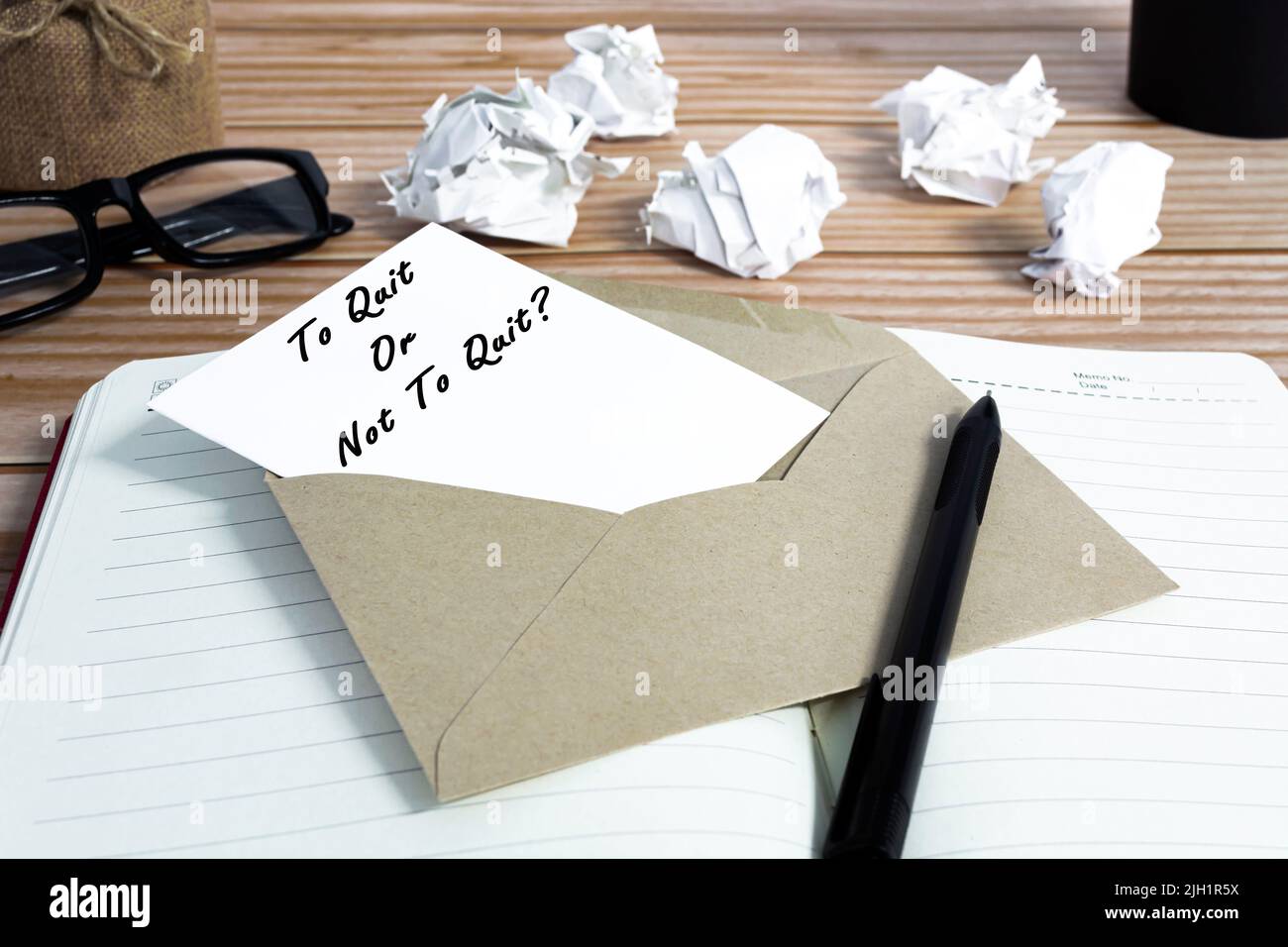 To quit or not to quit written on notepad with trash paper background ...