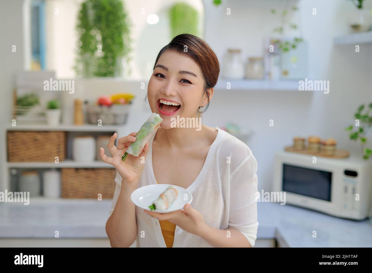 Asian woman eating tasty traditional spring rolls Stock Photo - Alamy